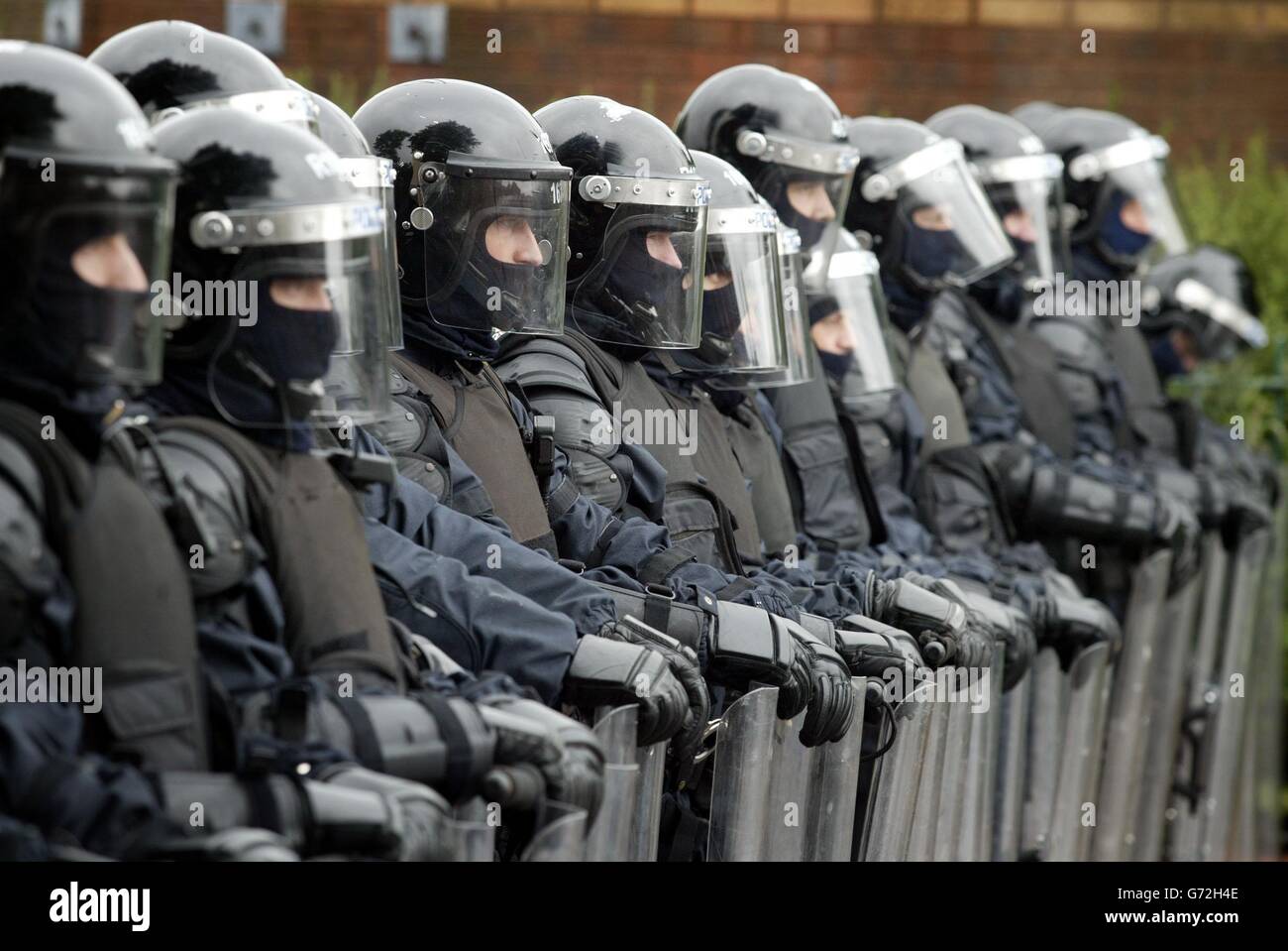 Police in riot gear watch as Orangemen pass through the peace line onto ...