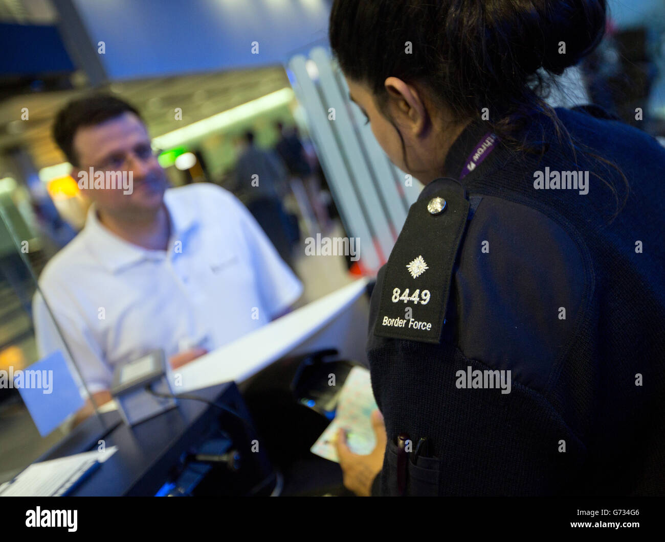 Border force officer passports of arrival passengers in terminal hi-res ...