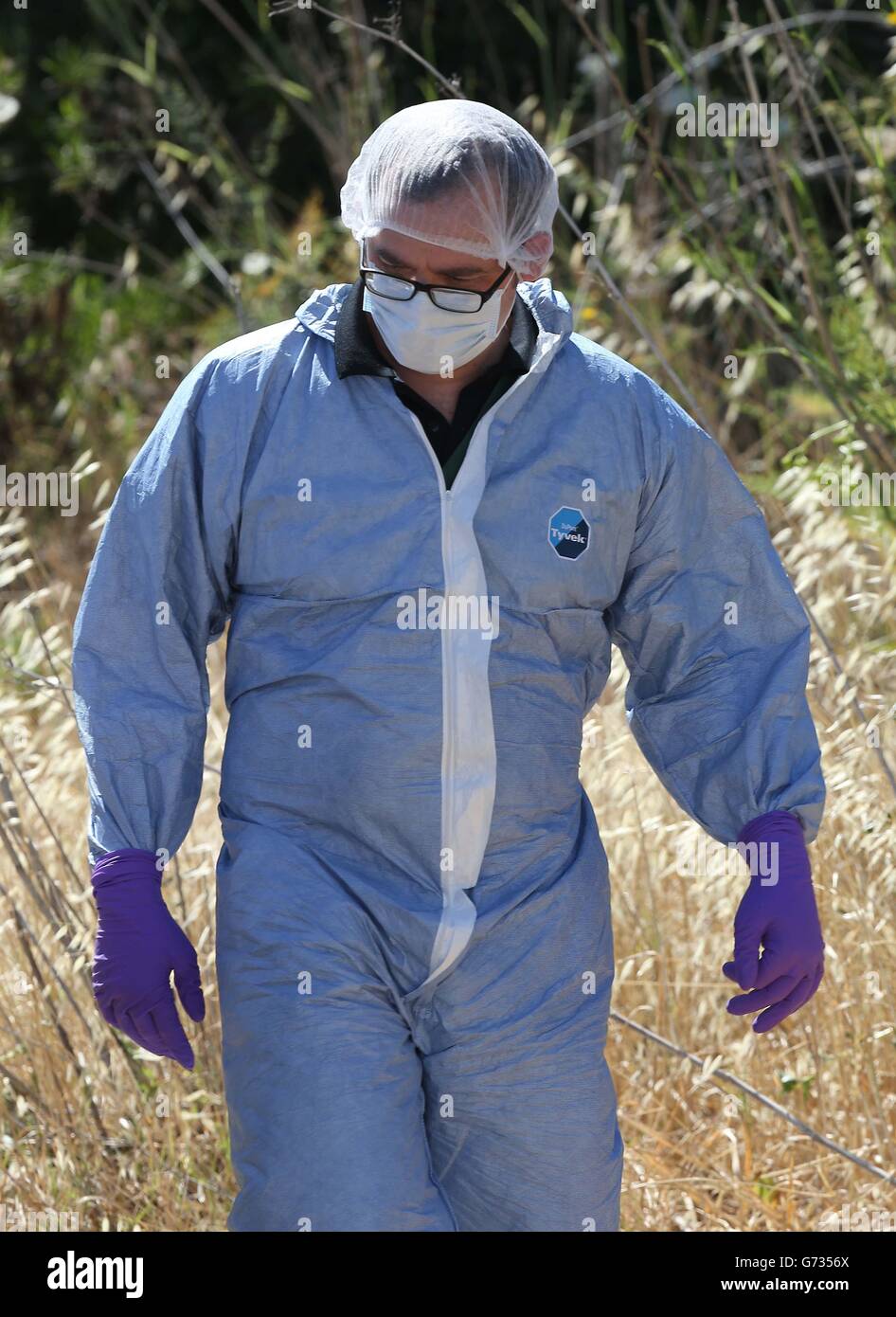 British forensic police officers preparing to examine a hole in an area ...