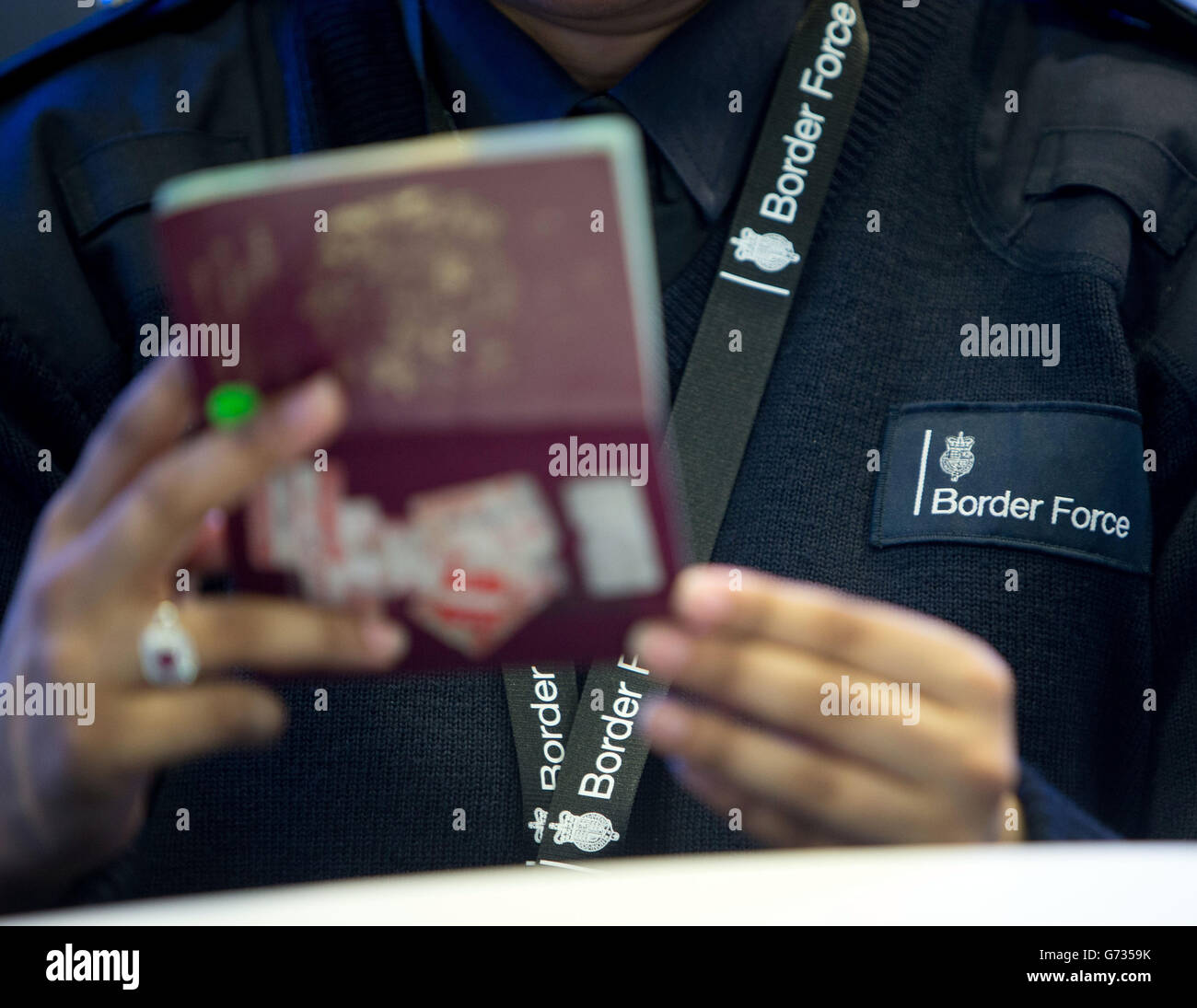 A Border Force officer checks passports of arrival passengers in ...