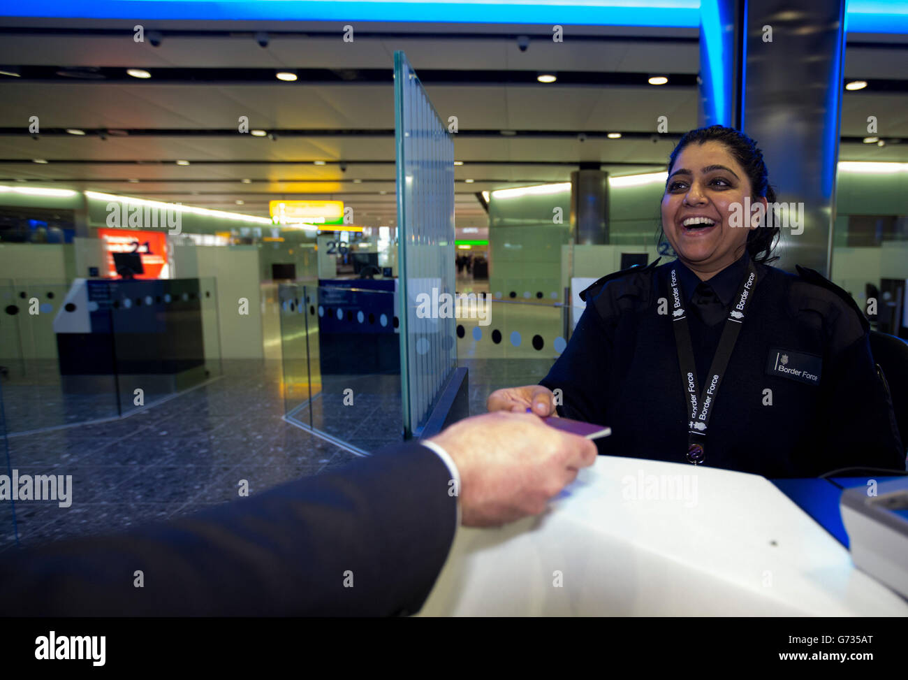 A Border Force officer checks passports of arrival passengers in ...