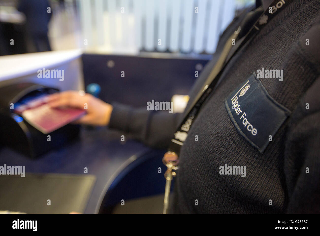 A Border Force officer checks passports of arrival passengers in ...