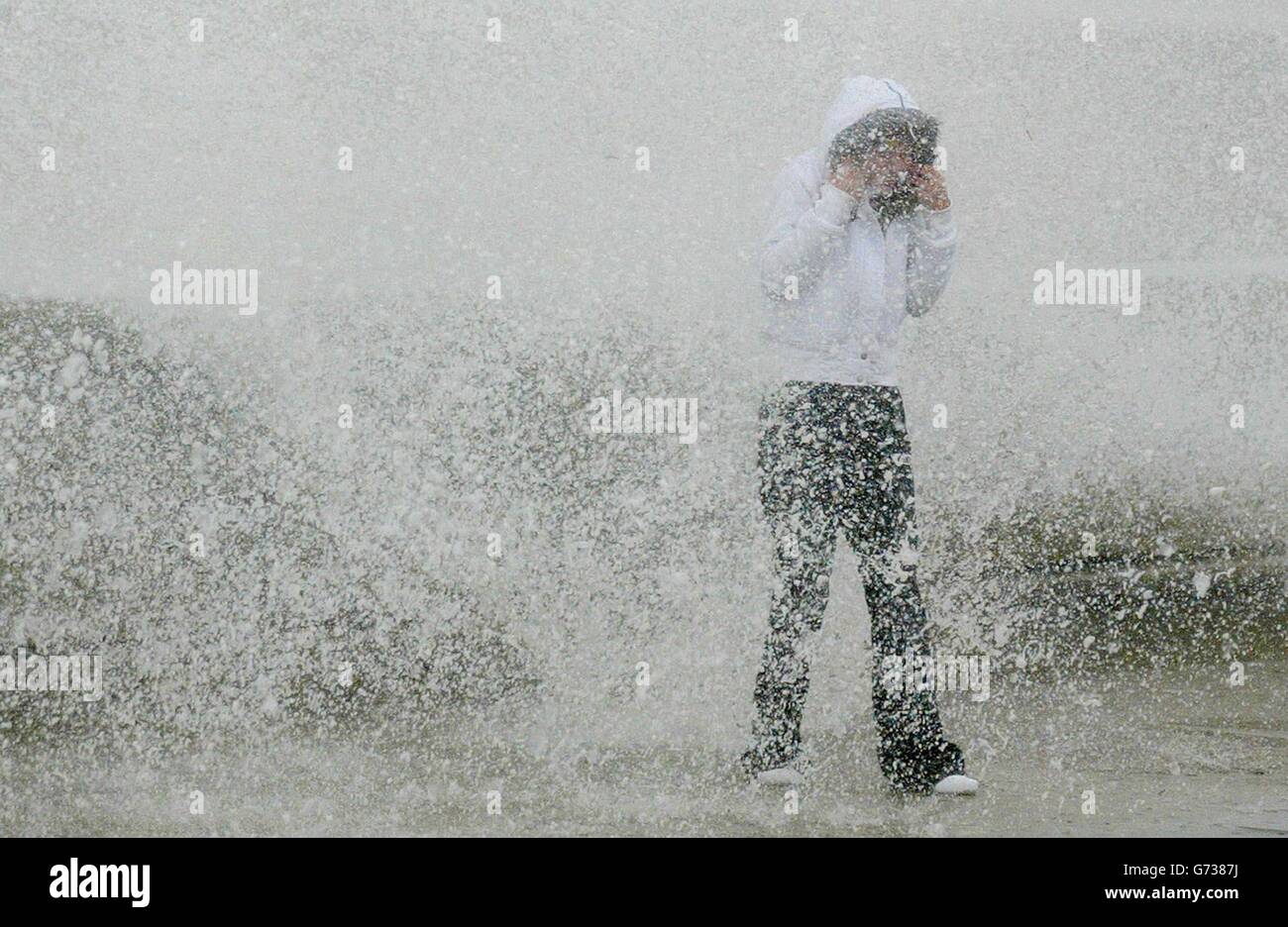 A women struggles to shield herself from high seas, as predicted gale ...