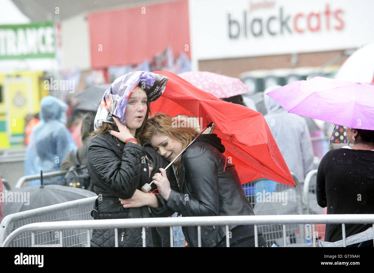 Fans of One Direction wait outside in the rain ahead of their concert ...