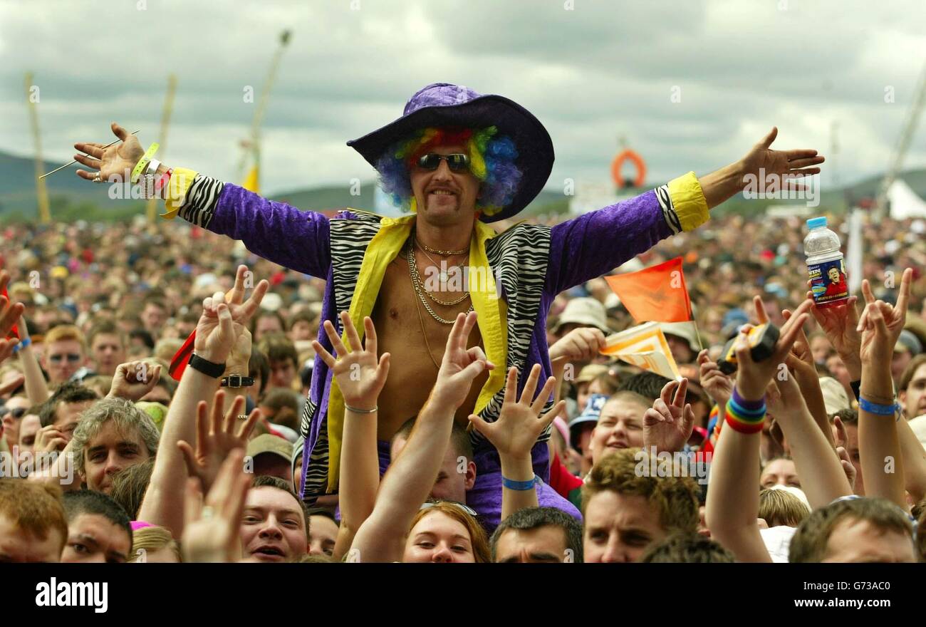 A reveller dressed as a pimp watching Franz Ferdinand on the main stage ...