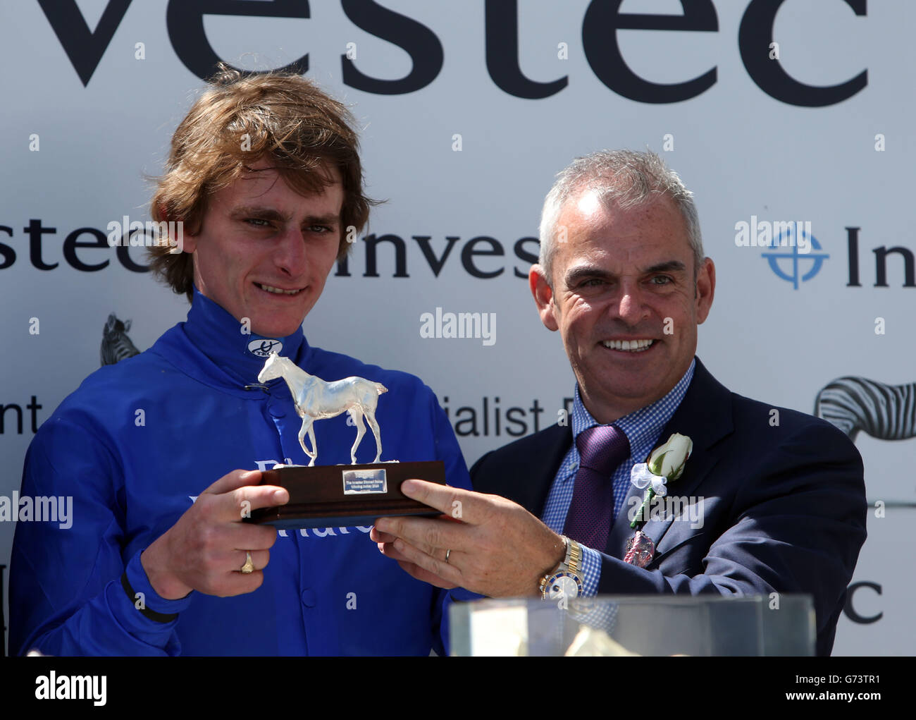 Golfer Paul McGinley presents jockey Adam Kirby with his trophy after ...