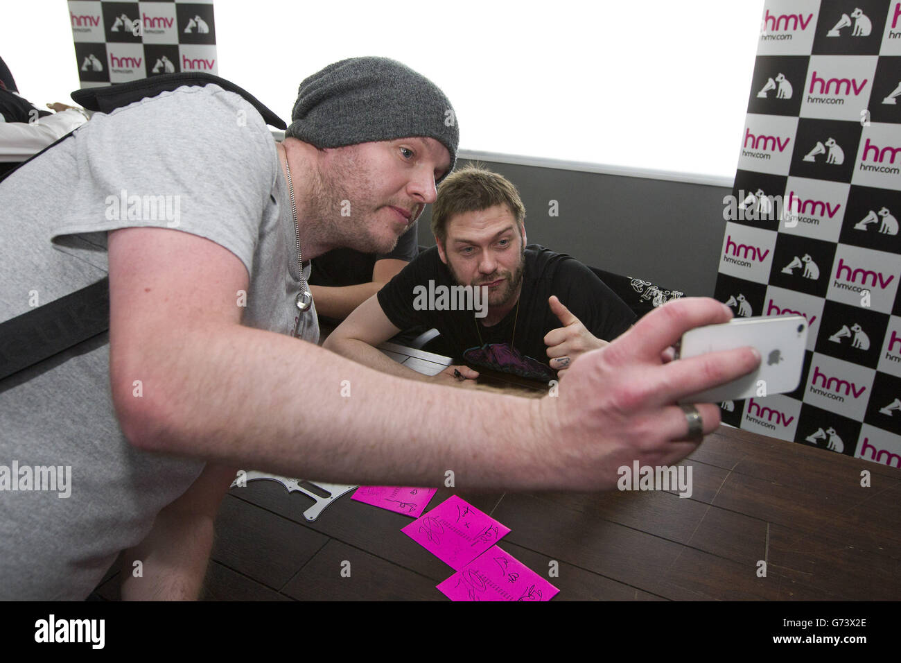 Tom Meighan (right) of Kasabian has a picture taken with a fan at HMV ...