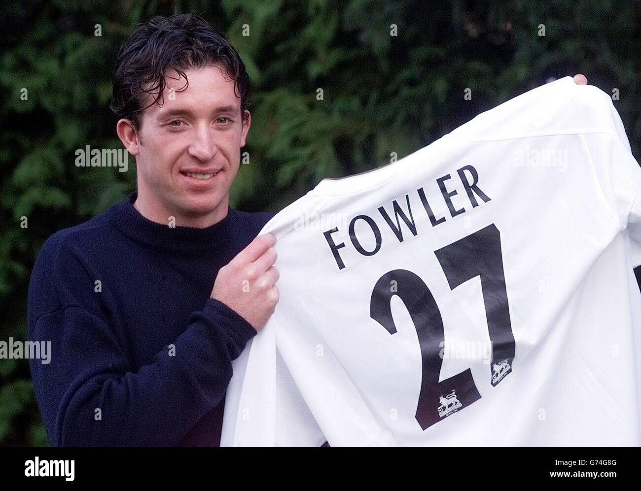 Leeds United's new signing Robbie Fowler holds his shirt up to the ...