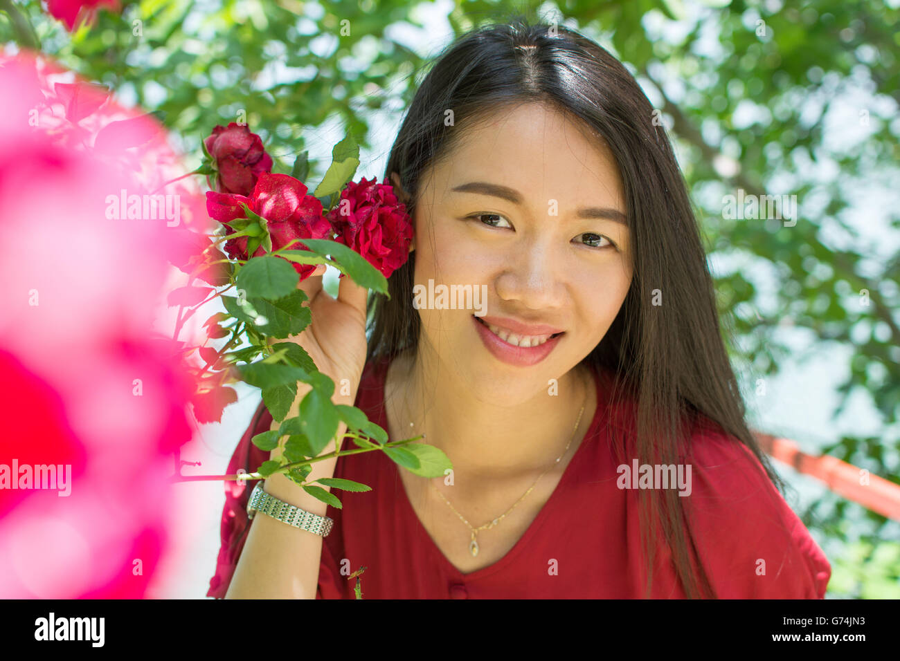 Woman in red dress holding a red rose close to her face Stock Photo - Alamy
