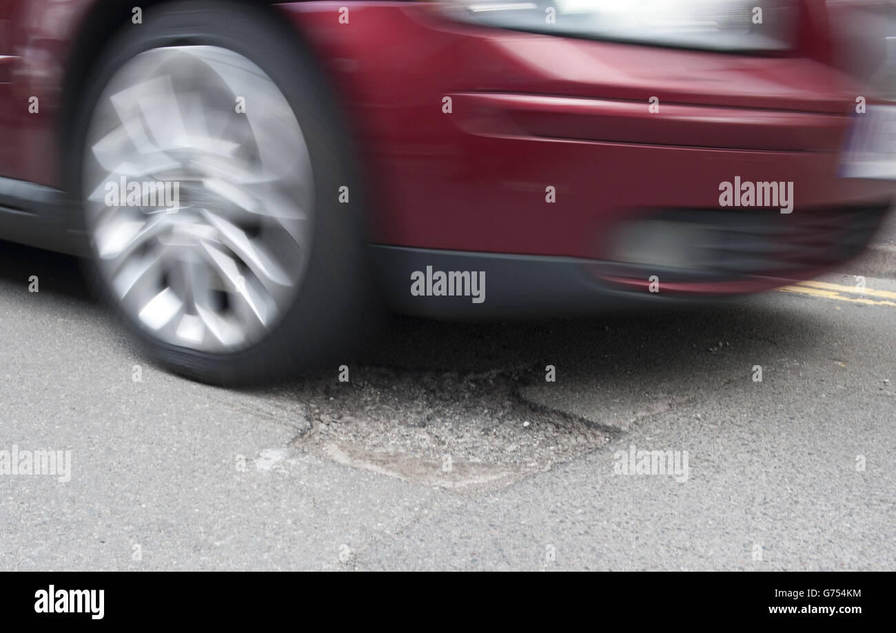 A car drives over a pothole on a road in Kimberley, Nottingham Stock ...