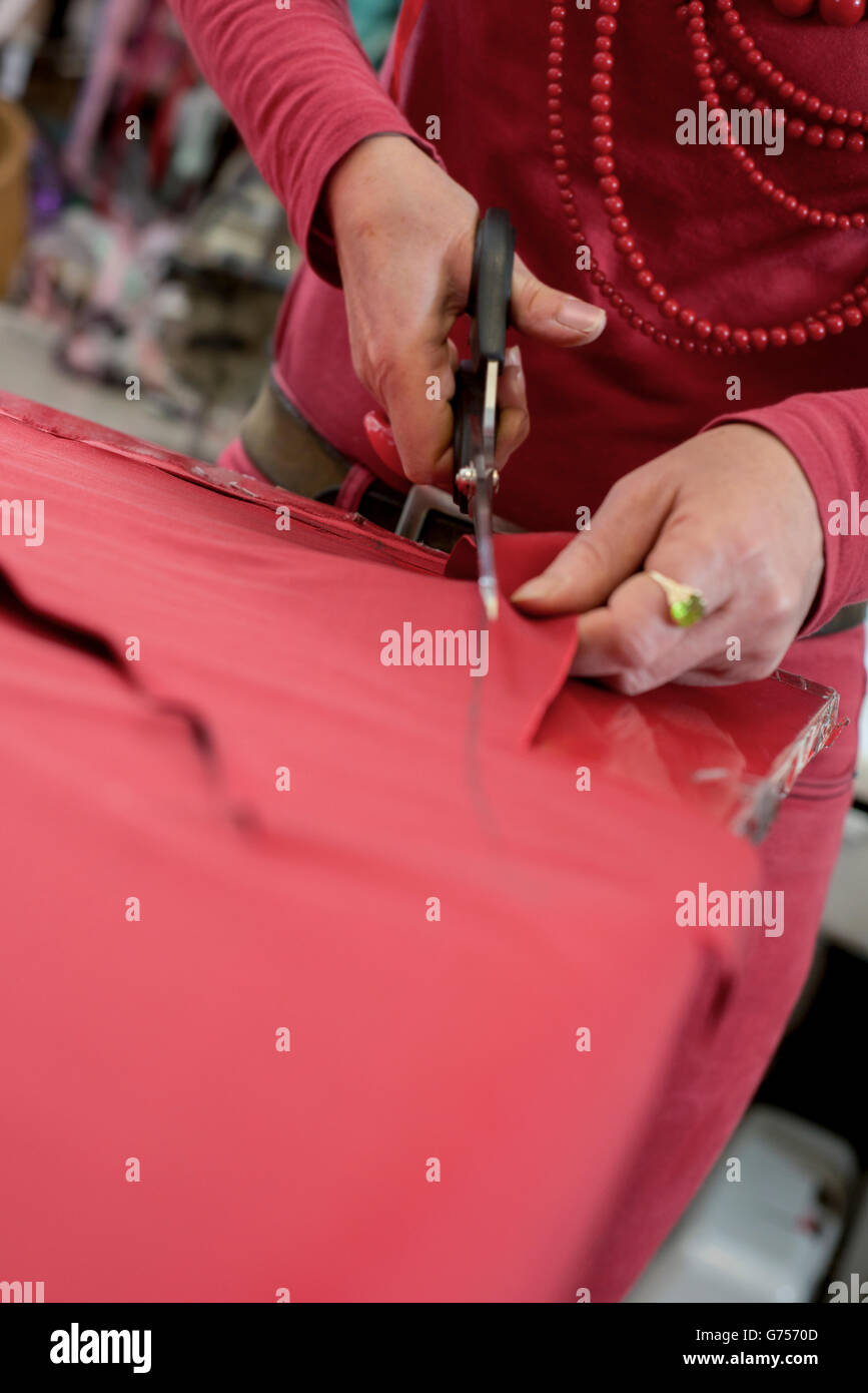 A pair of scissors in tailor's hands cutting through red cloth Stock ...