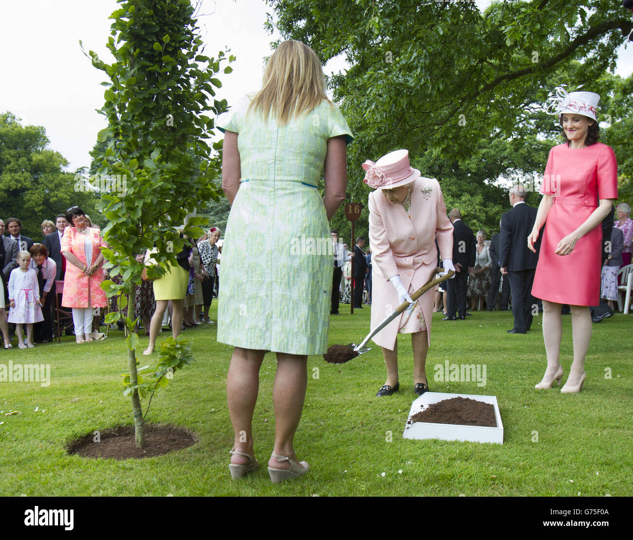 Queen Elizabeth II plants a tree during a garden party held at ...