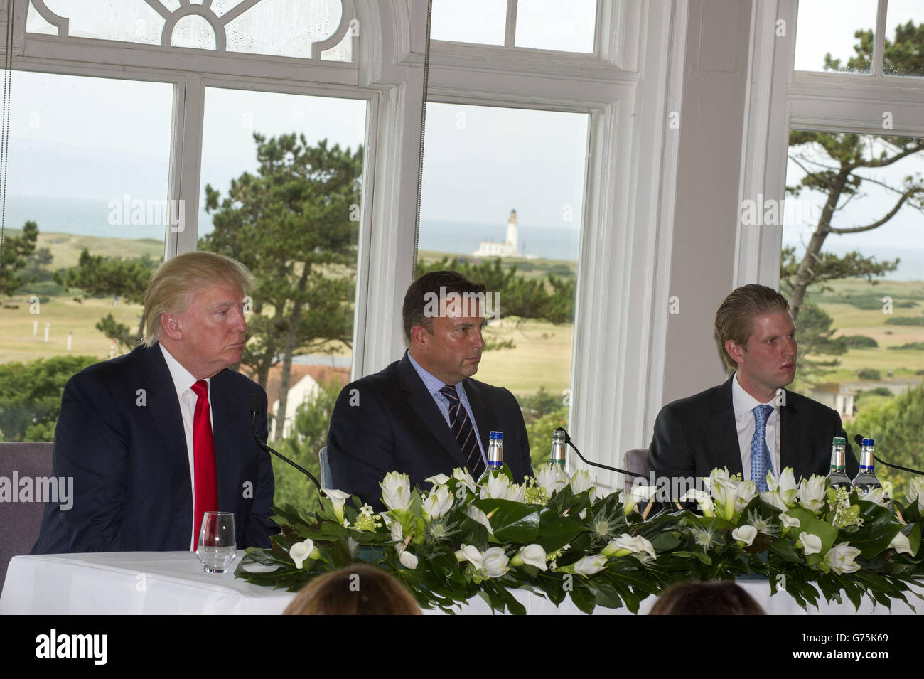 Donald Trump is flanked by his son Eric (R) and golf architecht Martin ...