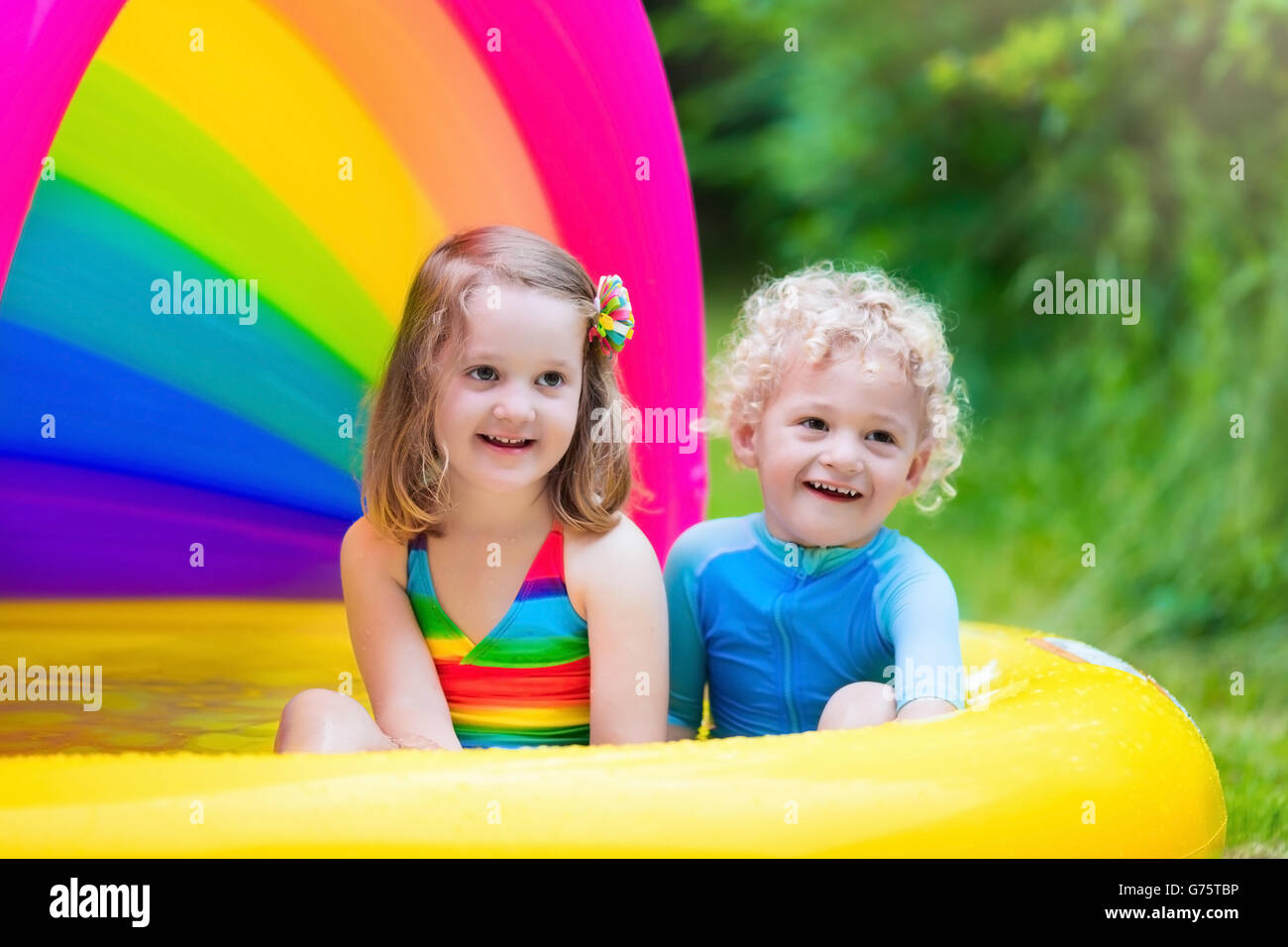 Children playing in inflatable baby pool. Kids swim and splash in ...