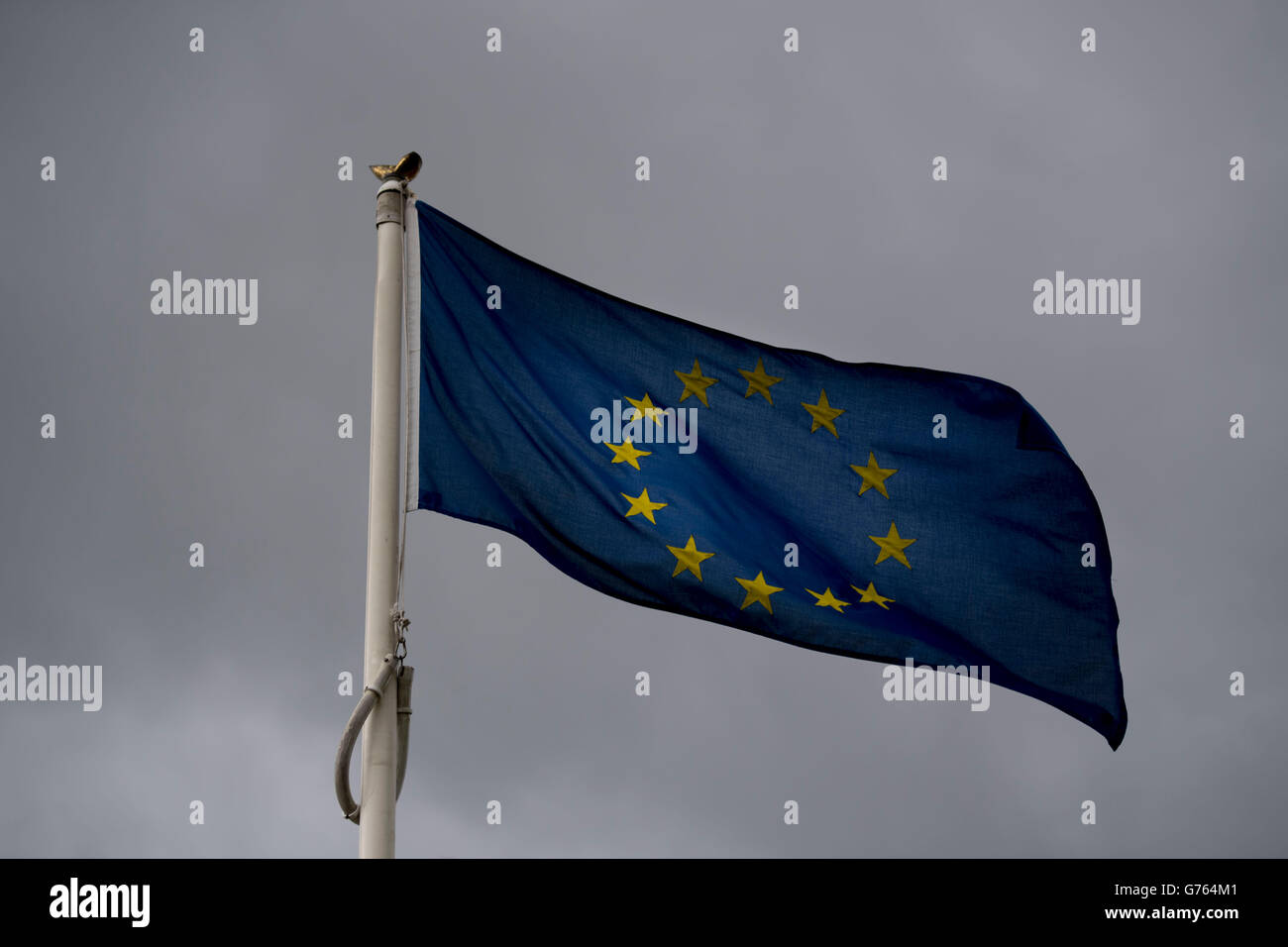 European Union (EU) flag blowing in the wind with dark storm clouds ...