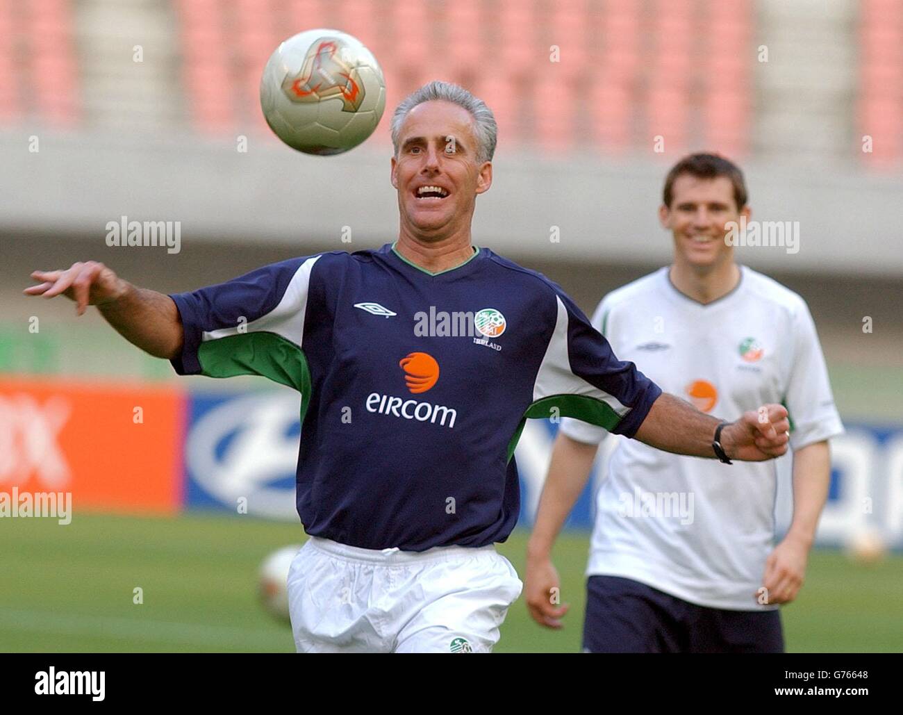 Ireland's Kevin Kilbane (background) smiles as he watches manager Mick ...