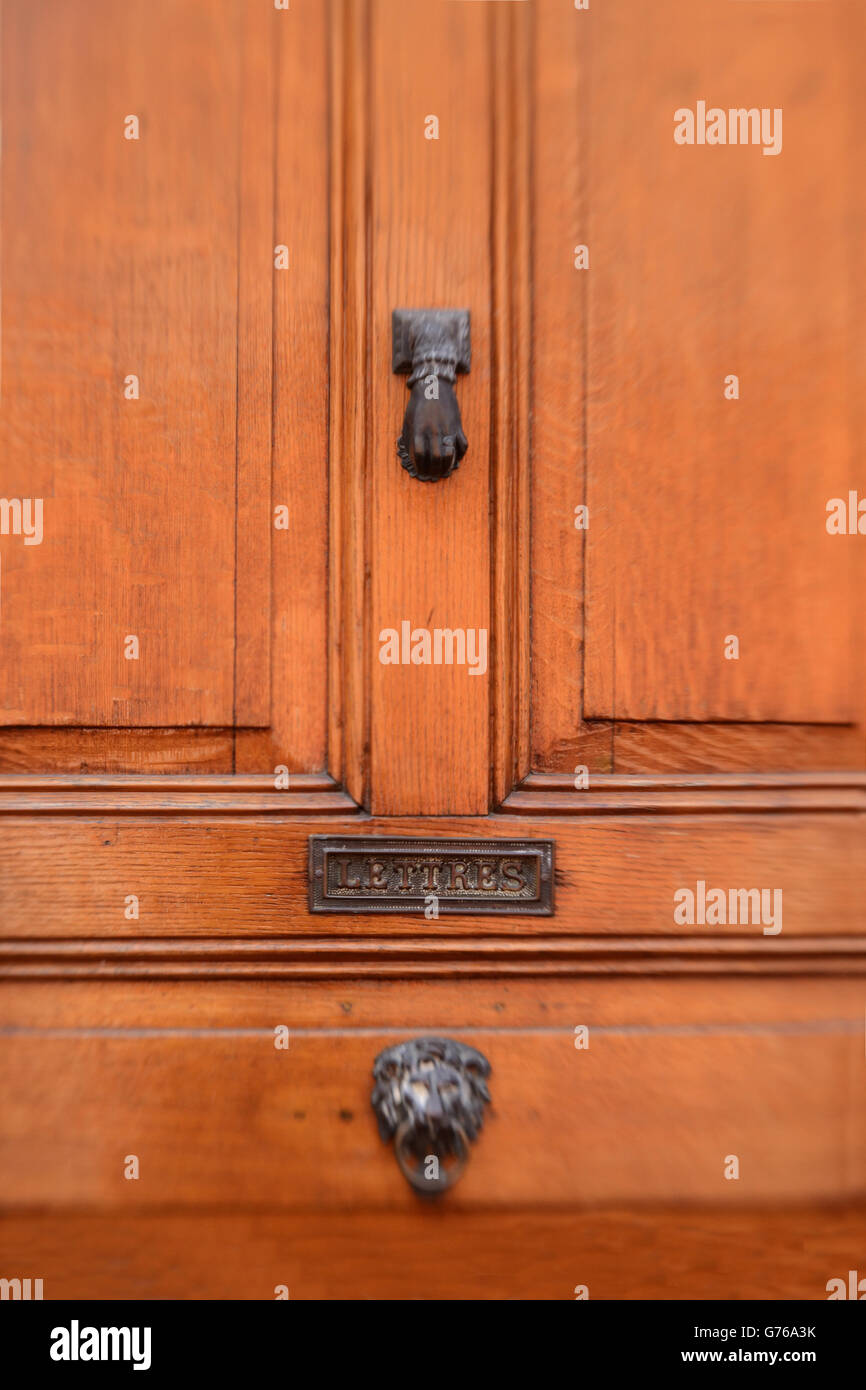 Dark wooden door with hand as door knocker, also showing mail slot in ...