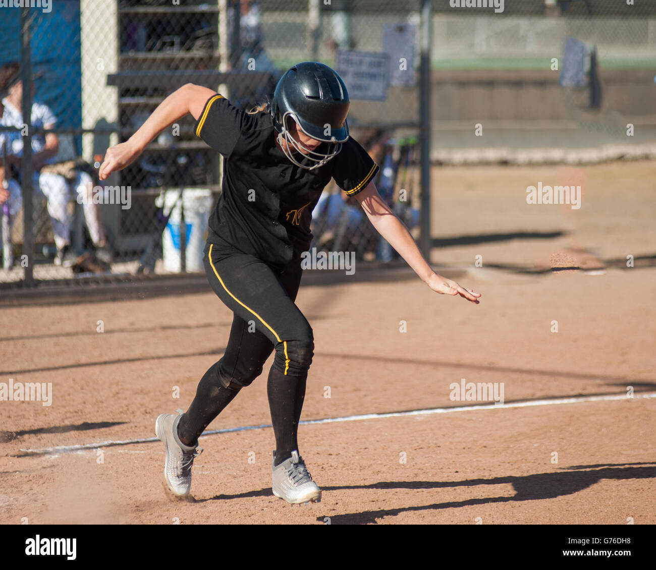 Softball player in black uniform sprinting to first base Stock Photo ...