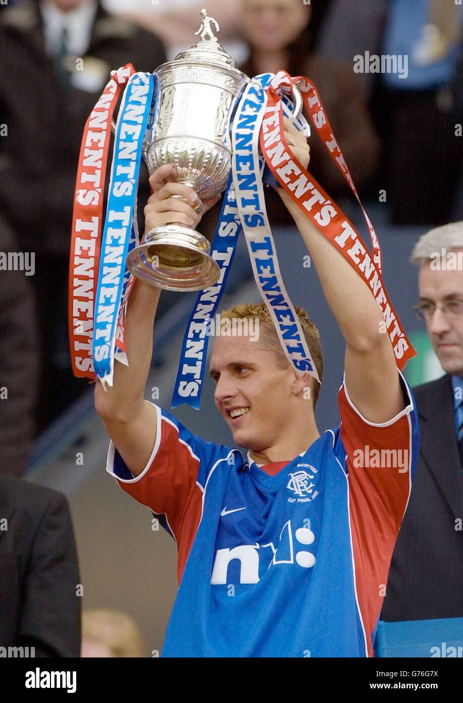 Rangers' double-goalscorer Peter Lovenkrands holds the trophy aloft ...