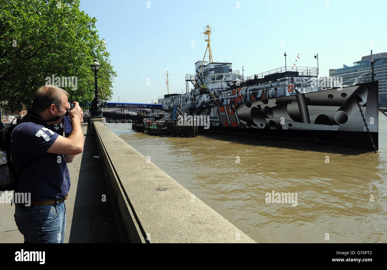 A man stops to photograph WWI warship HMS President (1918) which has ...