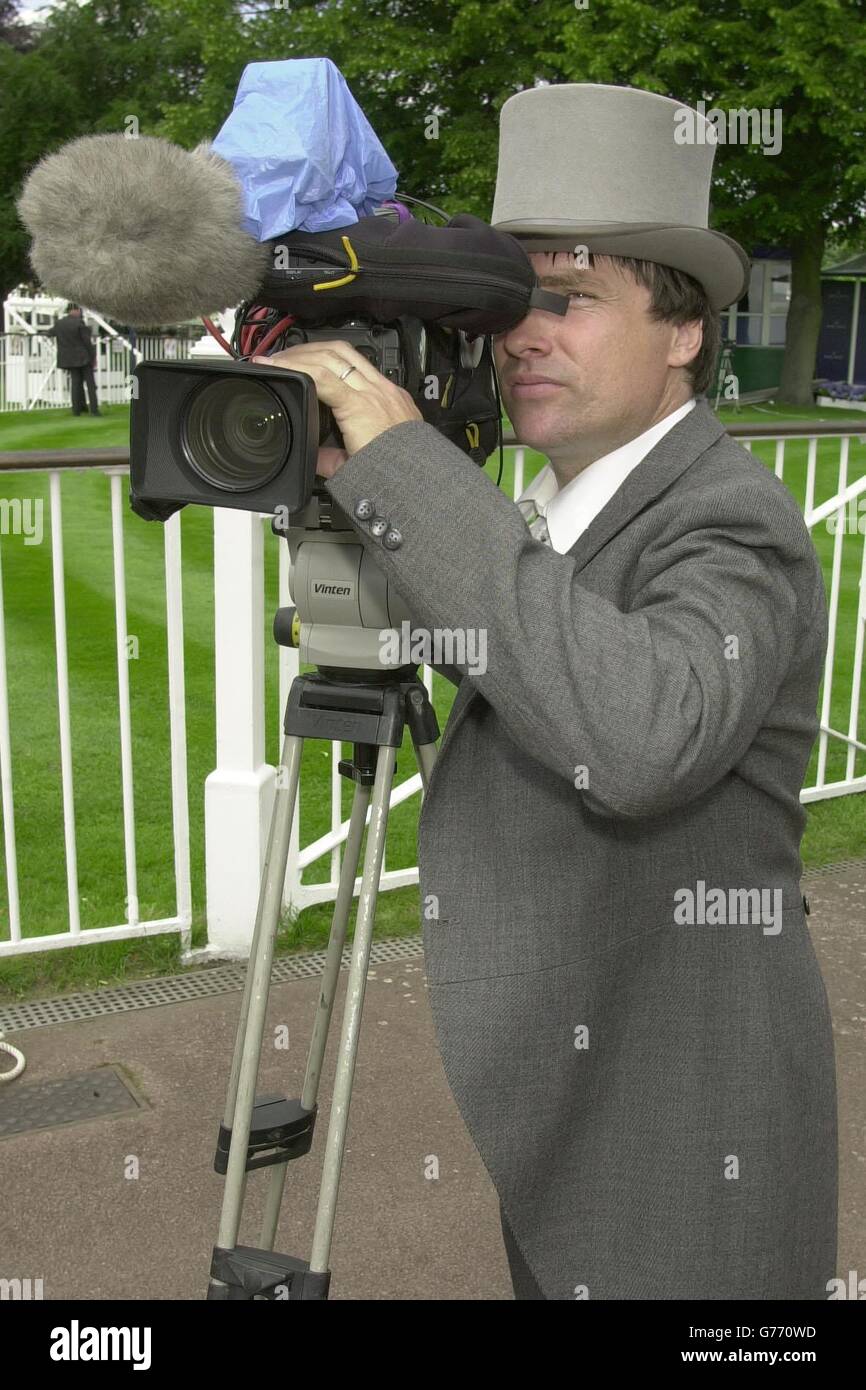 A BBC TV cameraman wears top hat and tails, in the paddock area at ...