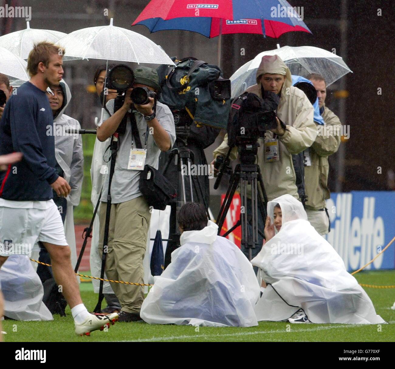 England captain David Beckham walks past photographers sheltering from ...