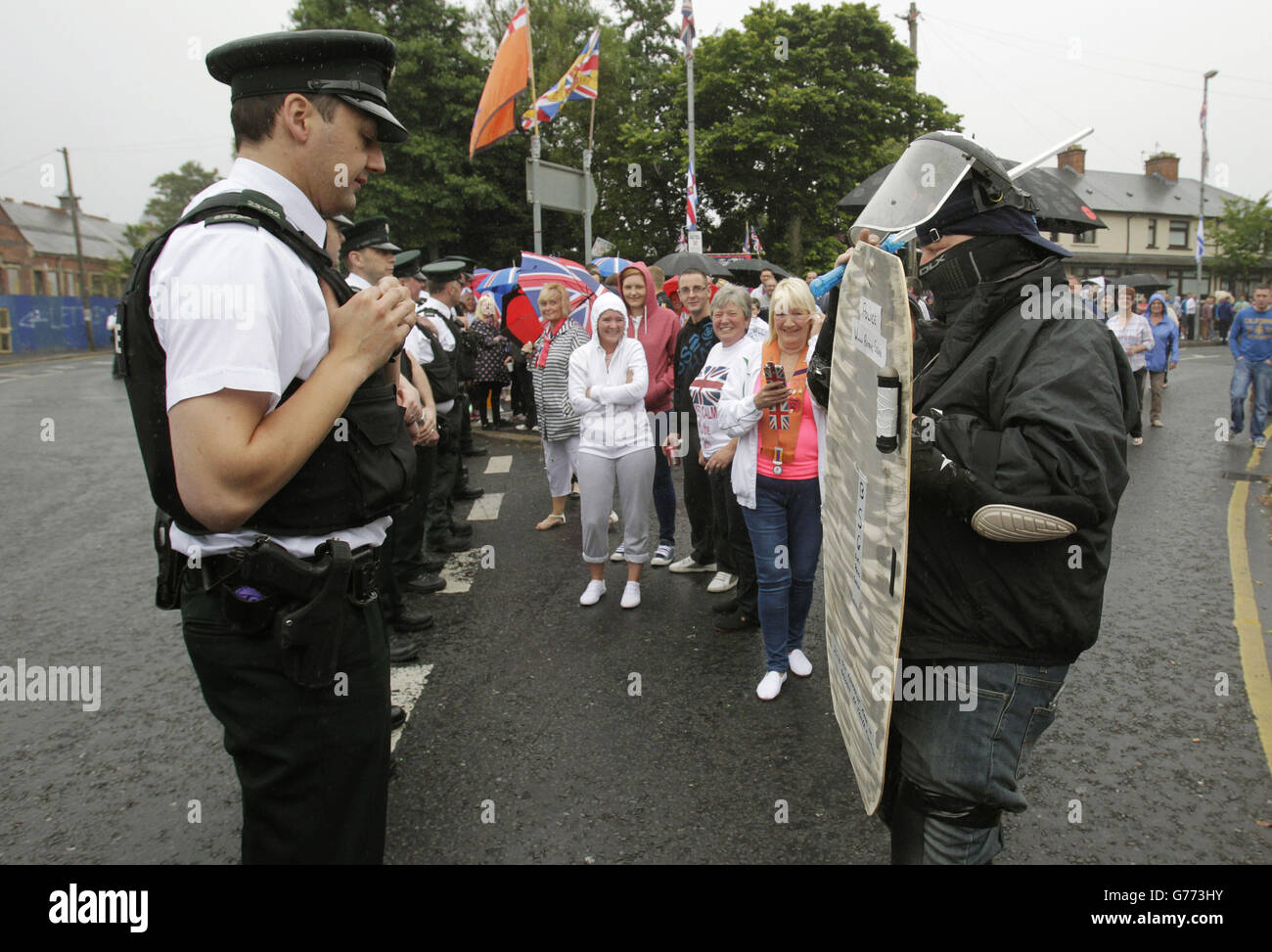 A loyalist supporter dressed as a riot police officer approaches police ...
