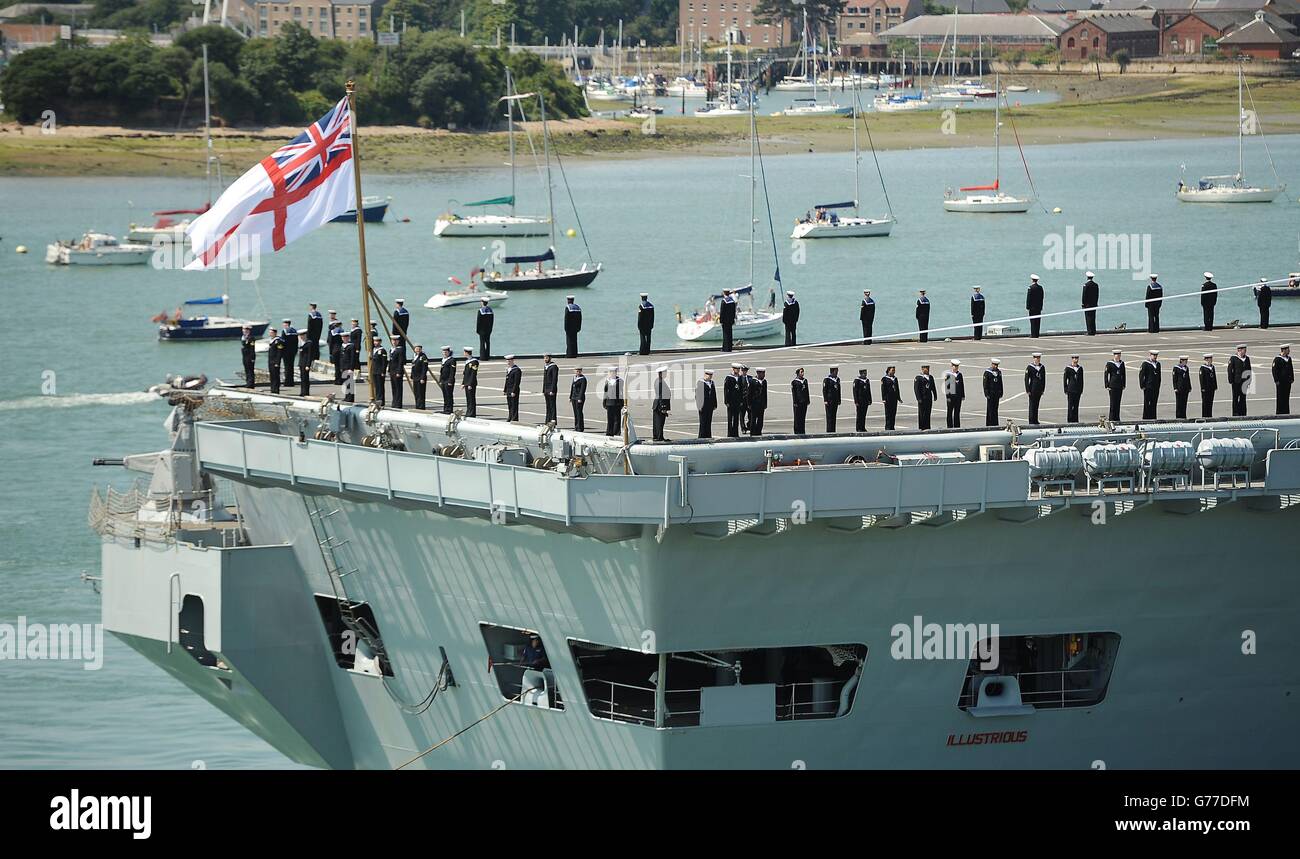 Crew members line the deck of HMS Illustrious as she sails into her ...