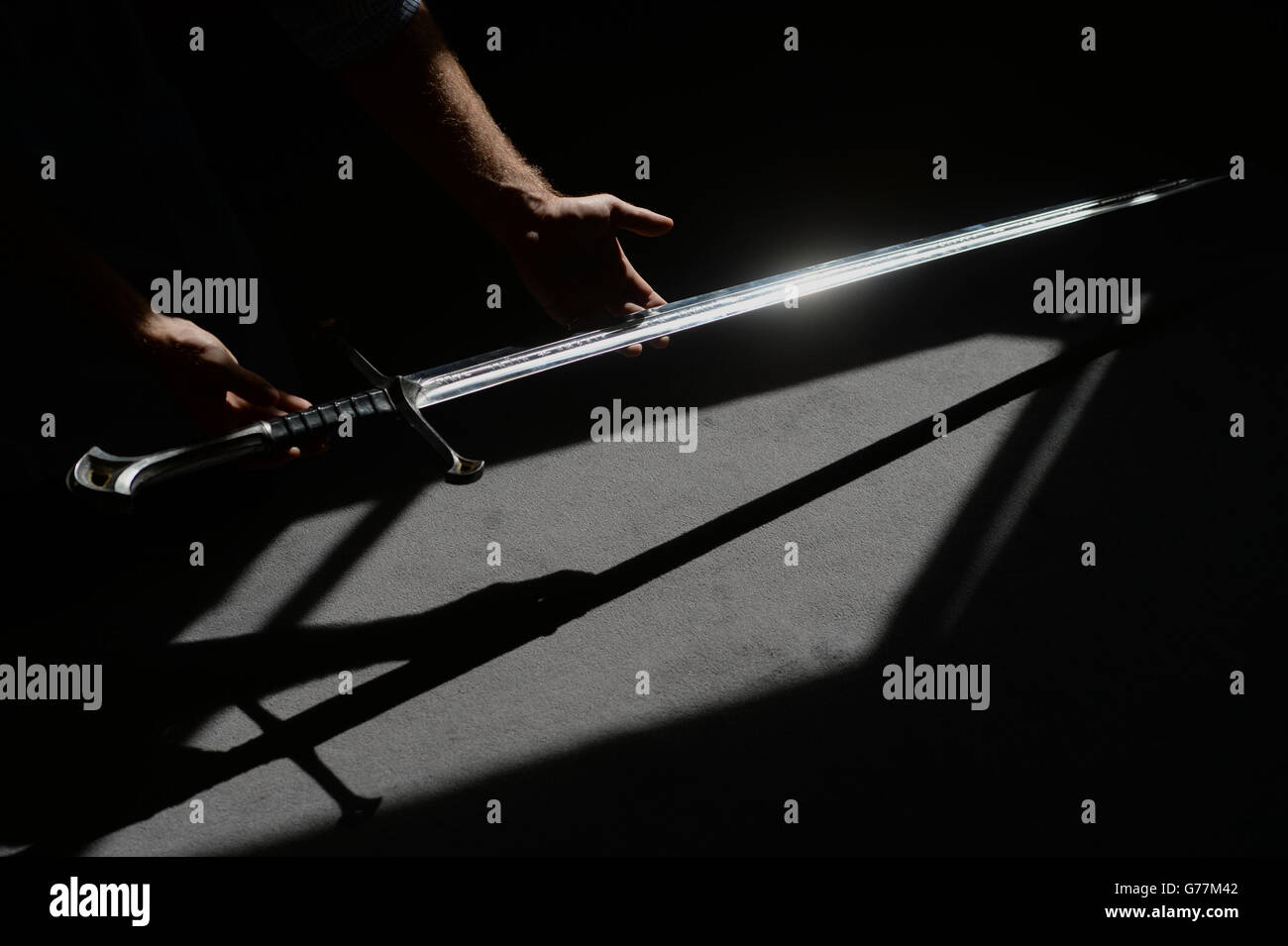 An employee poses with a Sword used in the Lord of the Rings trilogy as ...
