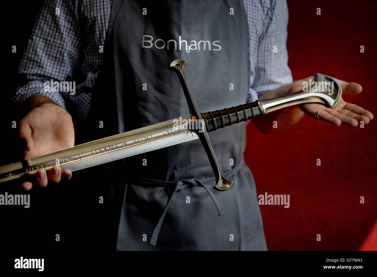 An employee poses with a Sword used in the Lord of the Rings trilogy as ...