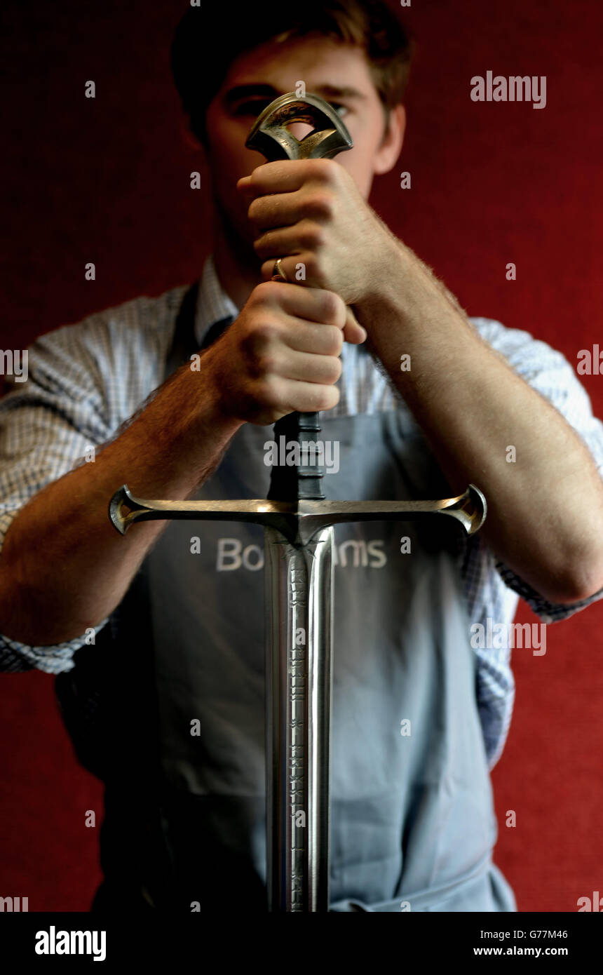 An employee poses with a Sword used in the Lord of the Rings trilogy as ...