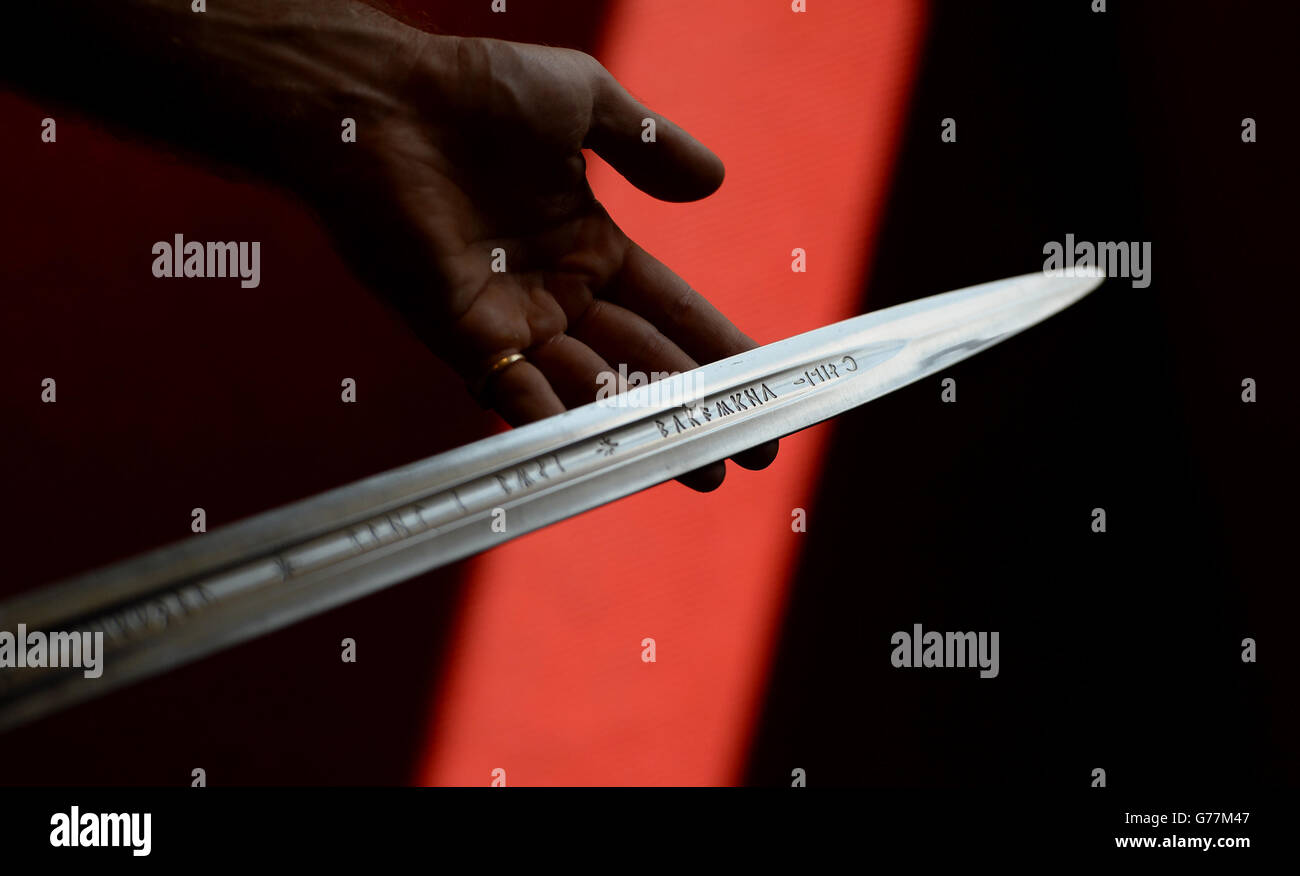 An employee poses with a Sword used in the Lord of the Rings trilogy as ...