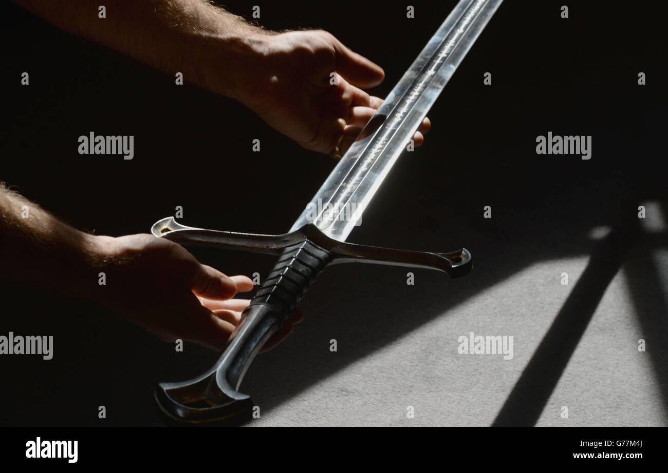 An employee poses with a Sword used in the Lord of the Rings trilogy as ...