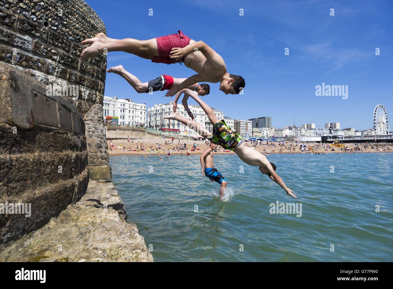 People jump off the sea defences into the water in Brighton, East ...