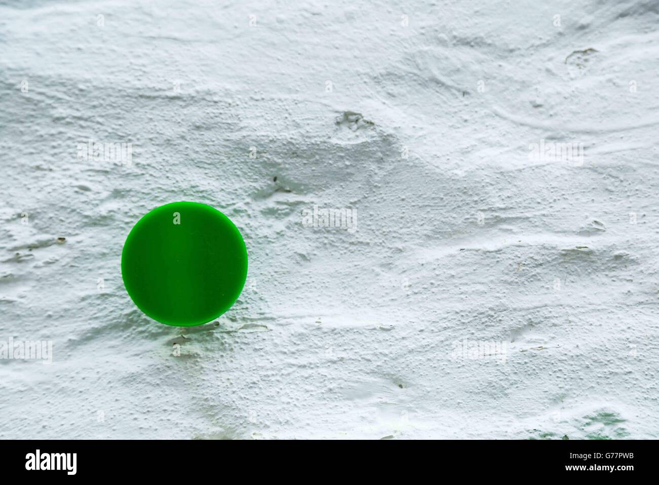 A green disc circle on a white, rough stone wall background Stock Photo ...