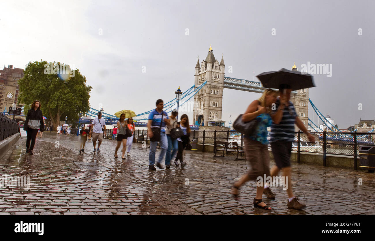 People cower under their umbrellas as they walk past Tower Bridge in ...
