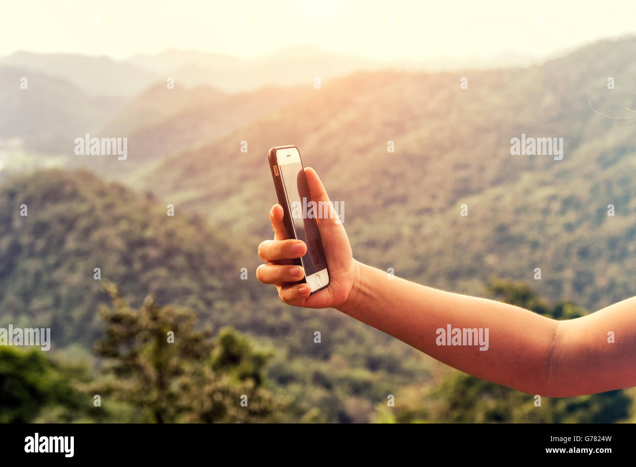 Close up of man using mobile smart phone with landscape background ...