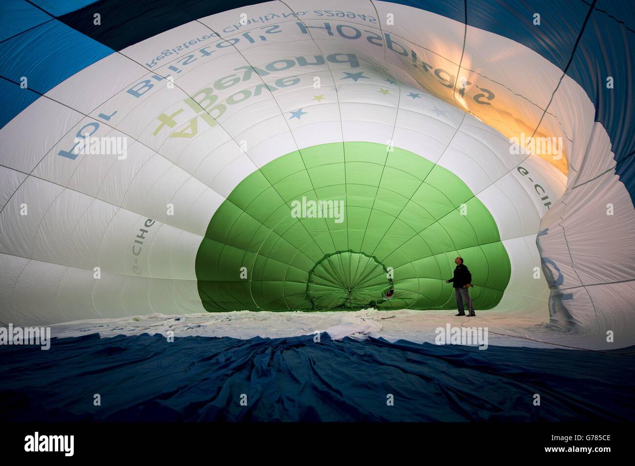 A balloon pilot checks the rigging inside a hot air balloon as it is ...
