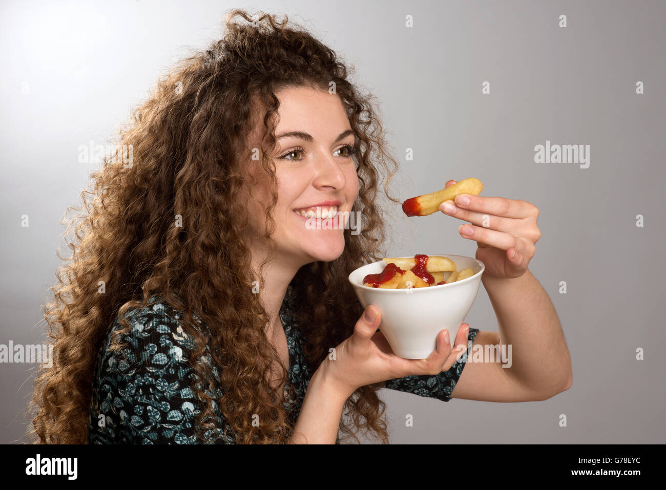 Attractive teenage girl eating potato chips with tomato sauce Stock ...