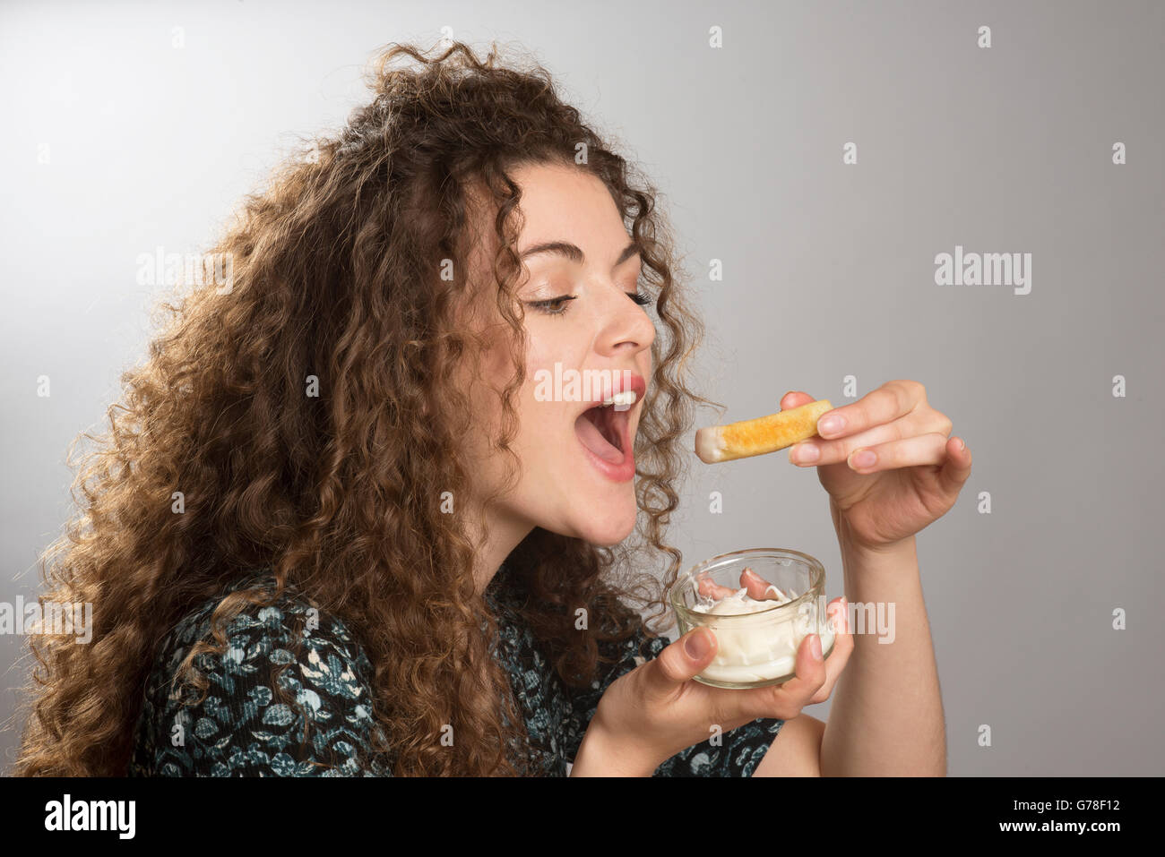 Young girl eating potato chips and dipping into mayonnaise Stock Photo ...