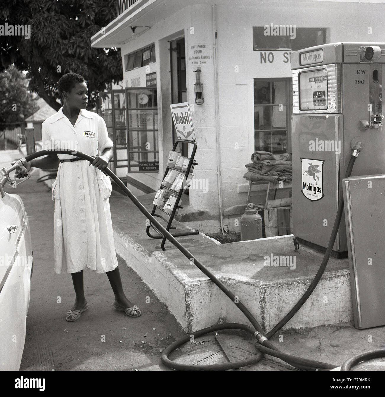 1950s, historical, female petrol attendant in uniform fills up motor ...