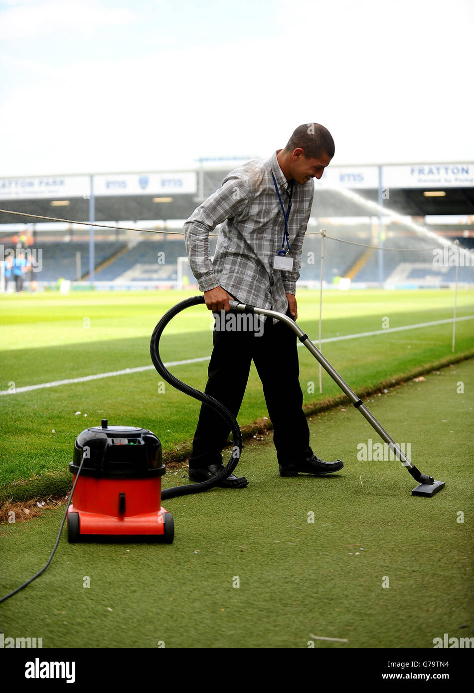 A member of staff vacuums an area of pitch side artificial turf before ...