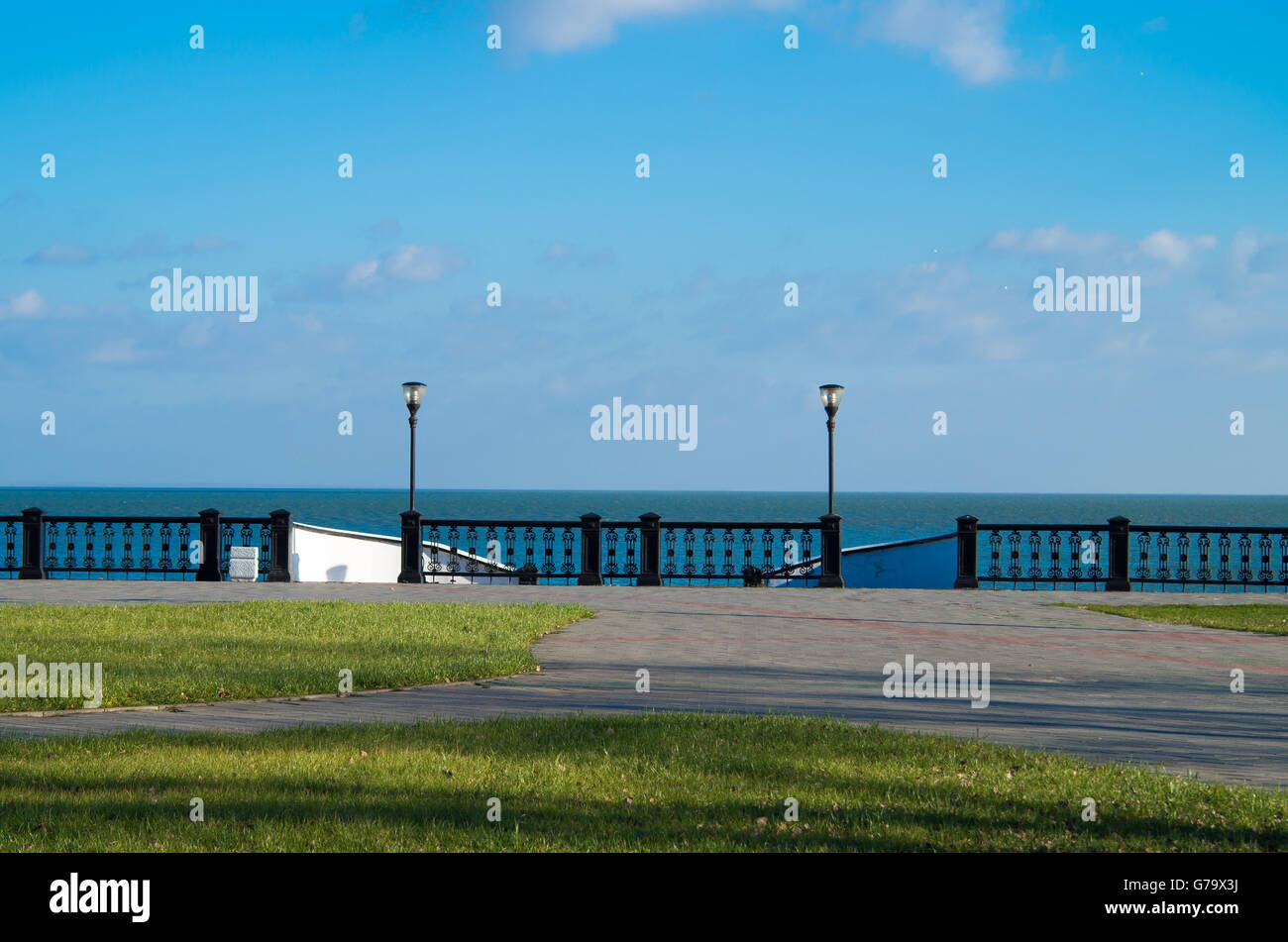 View of the embankment of the lake with a green lawn, stone pavement ...