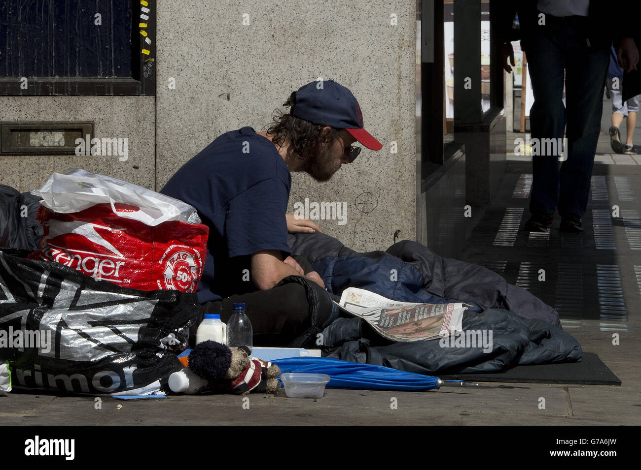 Members of the public walk past a homeless man in central London Stock ...