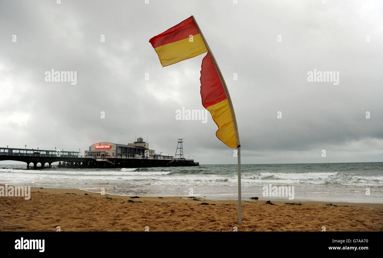 An RNLI lifeguard "Safest area to swim" flag lies on a near deserted ...