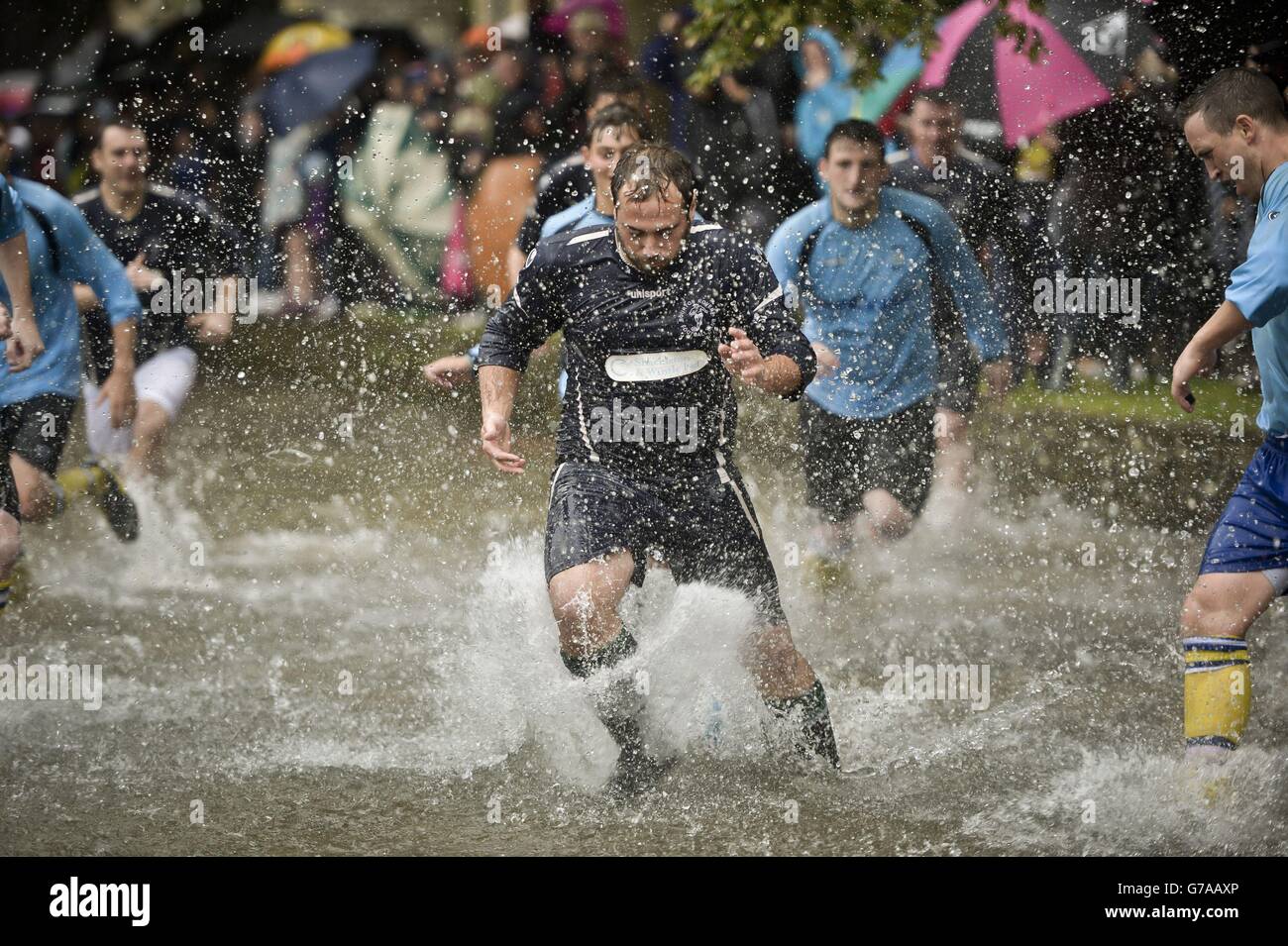 A Bourton Rovers 1st team player runs on the ball creating a big splash ...