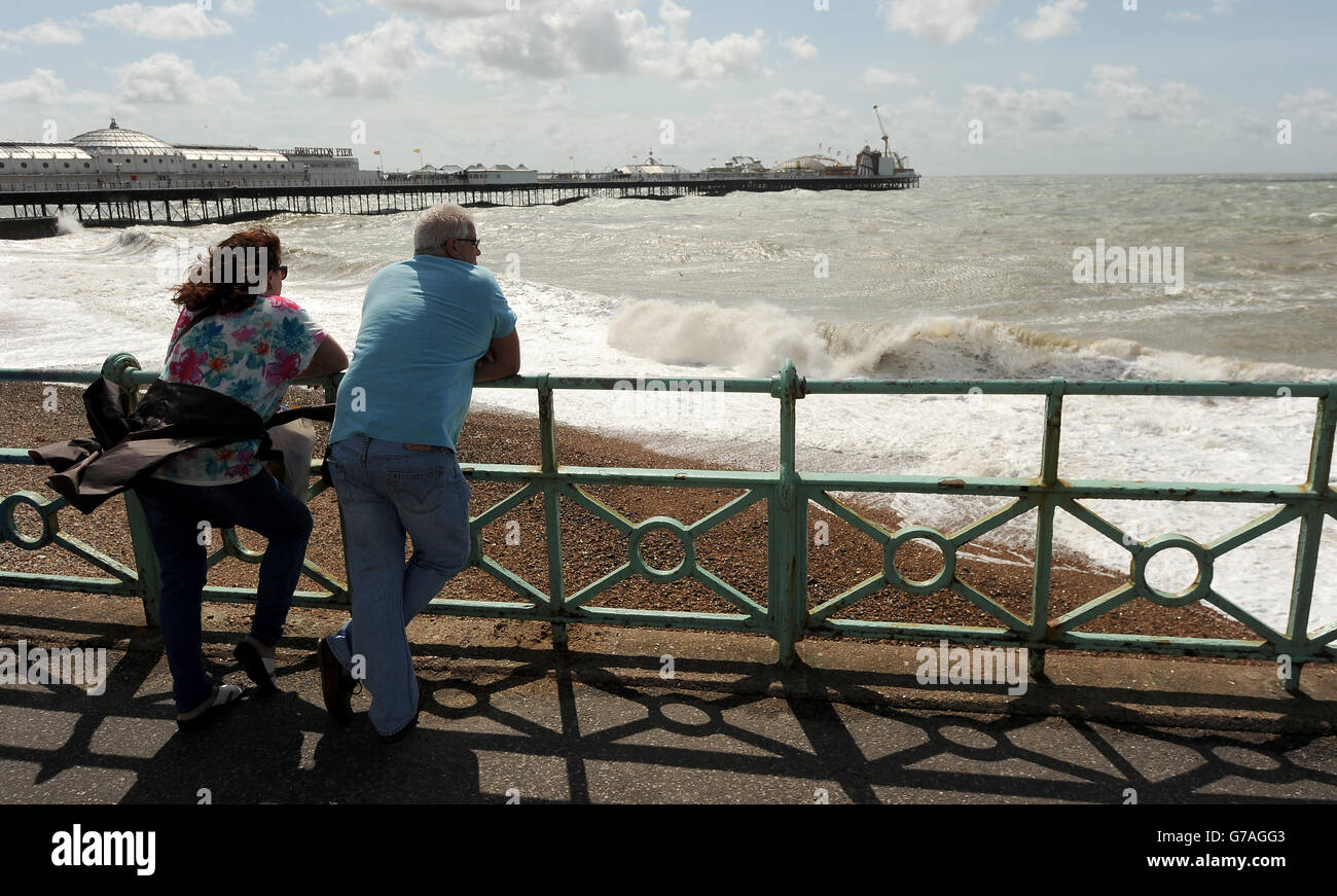 A couple watch the waves crashing on Brighton beach as the effects of ...