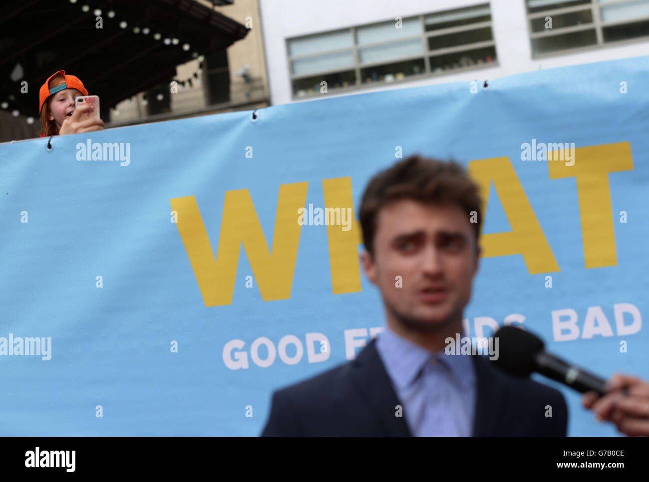A young fan peeks over a fence to catch a view of Daniel Radcliffe ...