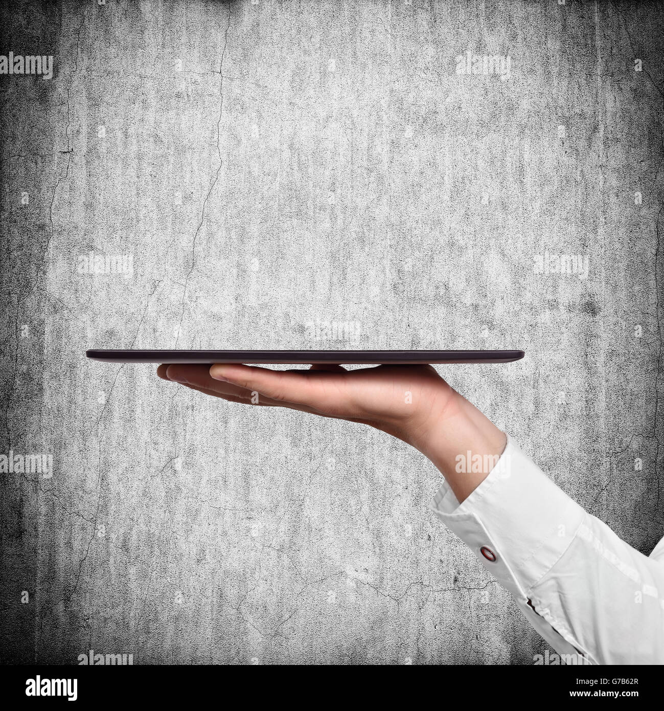 hand holding tablet on a concrete wall background Stock Photo - Alamy