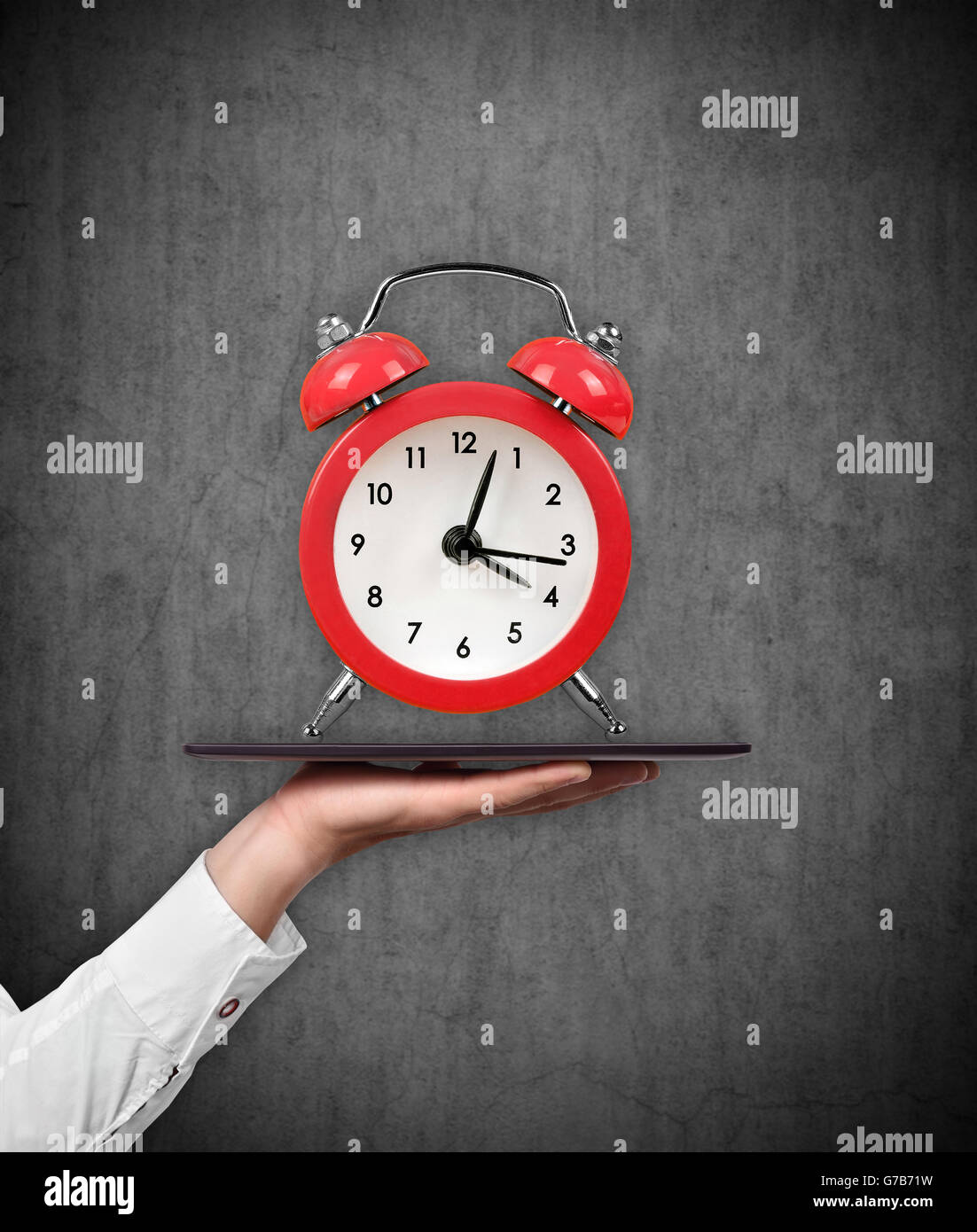 hand holding tablet and red alarm clock Stock Photo - Alamy